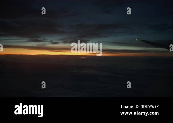 Silhouette of commercial airplane wing flying high above clouds during ...