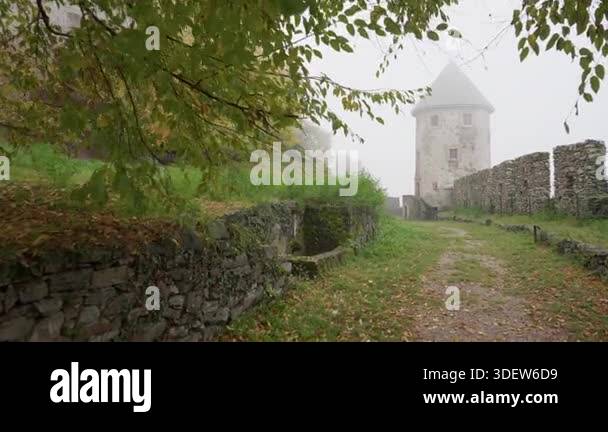 Ancient round stone tower and medieval fortification walls in thick fog ...