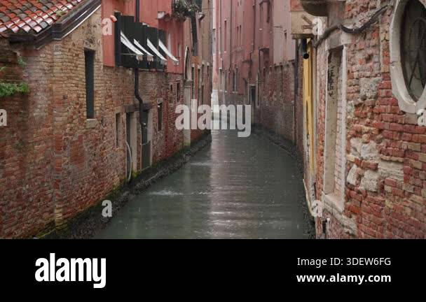 Empty narrow canal in Venice during heavy rain. Traditional historic ...