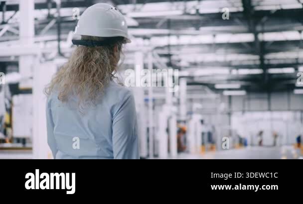 Female Factory Manager With Curly Hair in White Hard Hat, Walks Alone ...