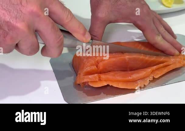 Chef slicing fresh salmon fillet with precision on a cutting board in a ...