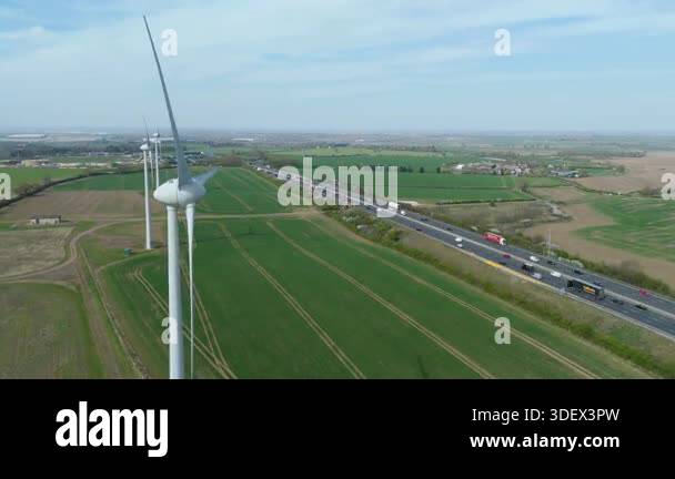 Aerial drone view of large wind turbine array and busy motorway highway ...
