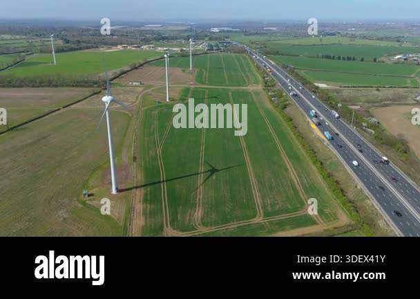 Aerial drone view of large wind turbine array and busy motorway highway ...
