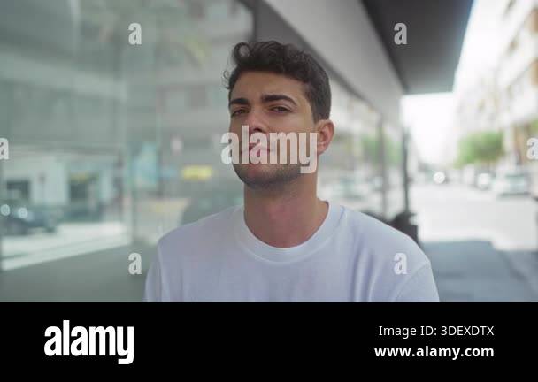 Man shows face closeup with steady gaze across street backdrop ...