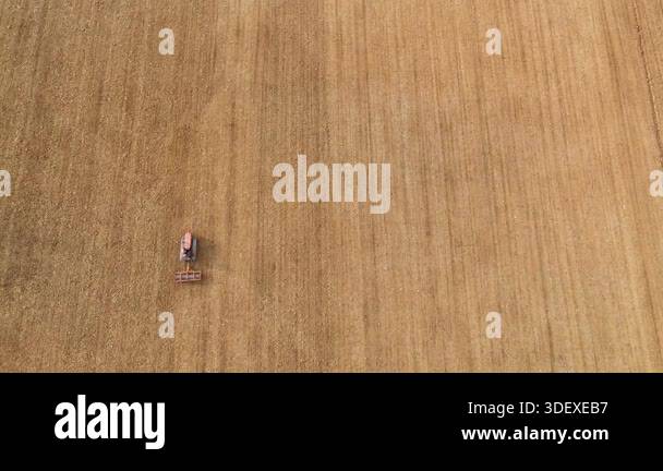 Tractor smoothing freshly plowed soil in a dry field, working the land ...