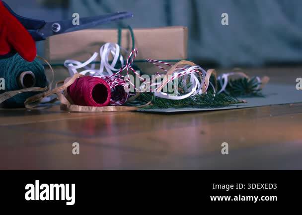 Hands with scissors on Christmas gift wrapping ribbon and string green ...