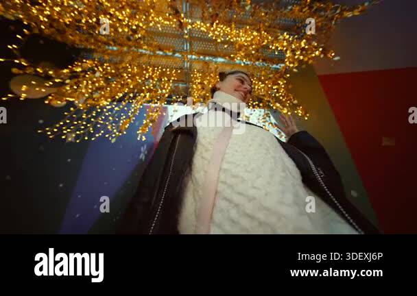 lowangle caucasian woman under golden canopy lights wearing leather ...