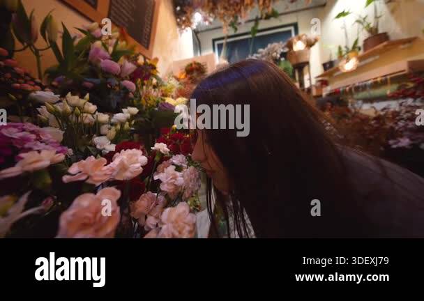 Woman smelling flowers in cozy florist shop, surrounded by vibrant ...