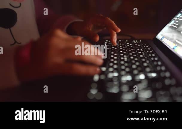 hands practicing typing on illuminated laptop keys, deliberate slow ...