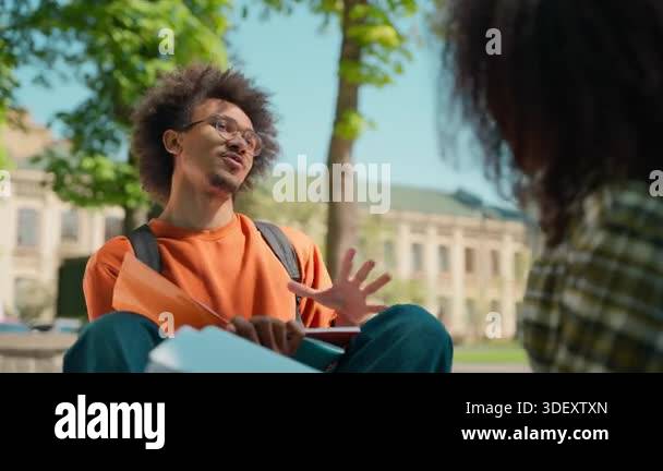 Two African American students female male talking together outdoors ...