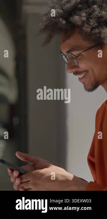 Happy smiling African American male student holding mobile phone in ...