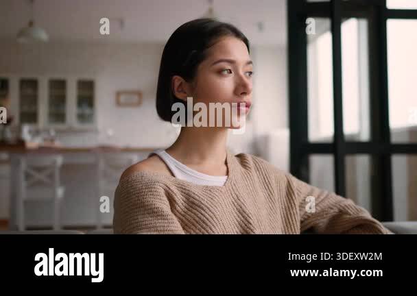 Serious Hispanic woman at home kitchen calm sad expression turning head ...
