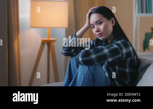 Alone tired sad Asian woman sitting sofa at home feeling exhausted ...