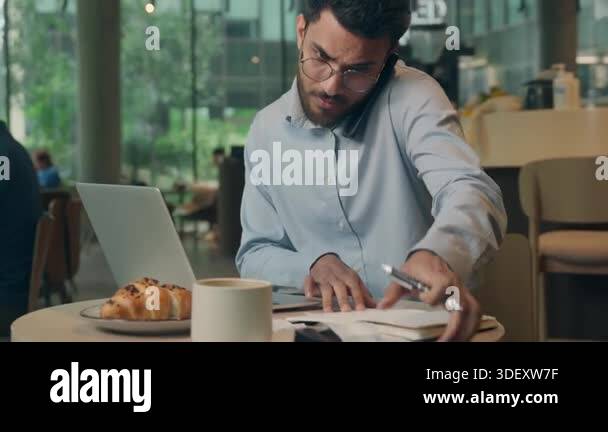 Indian ethnicity business man multitasking talking mobile phone writing ...