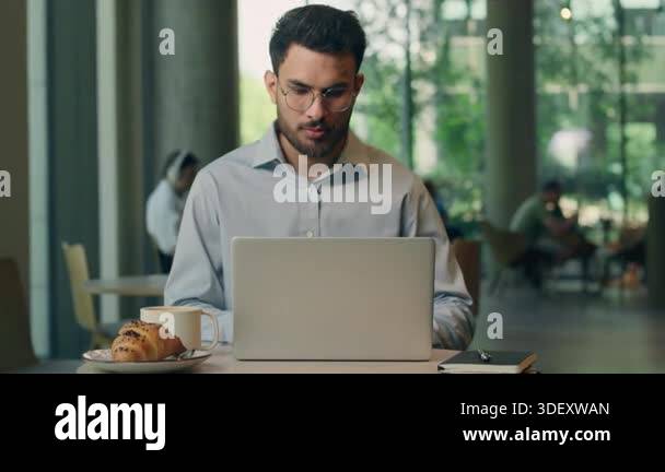 Concentrated Indian businessman with laptop working drinking tea coffee ...