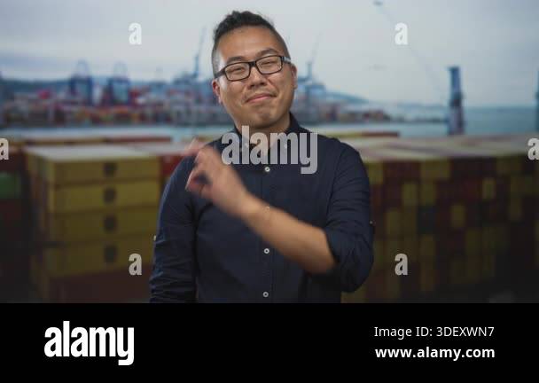 Man smiling and making ok sign with right hand beside stacked shipping ...