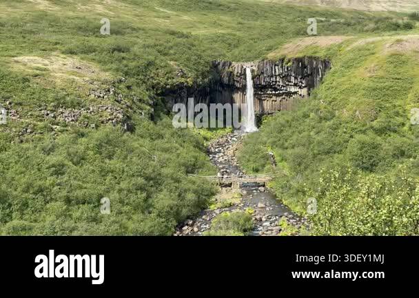 Distant Waterfall Cascading into Lush Green Highland Valley in Iceland ...