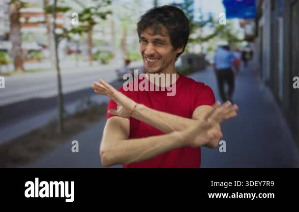 Man in red shirt smiling and waving hands enthusiastically in bright ...