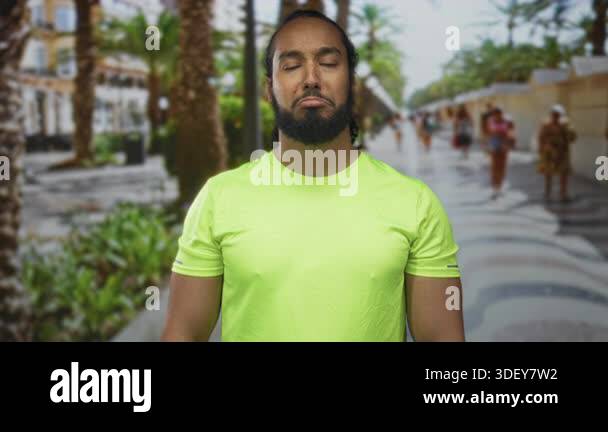 Man with beard and eyes closed, subtle frown, wearing neon green t ...