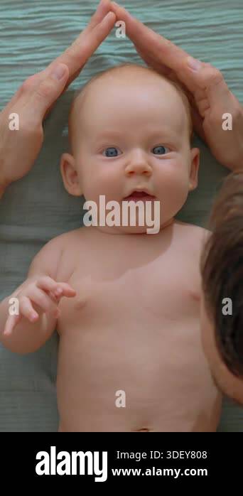 Father gently holds his hands above the head of his newborn baby ...