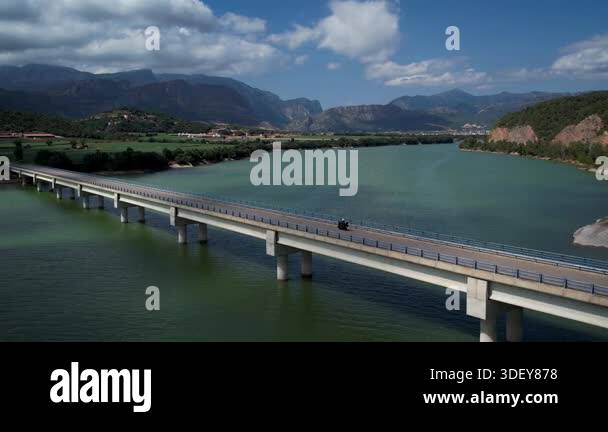 Aerial drone footage of motorcycle riding on bridge over a river in ...