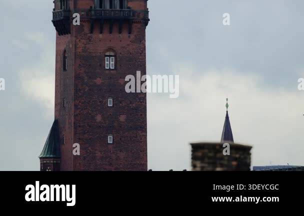 Red brick tower of Copenhagen city hall standing against a cloudy sky ...