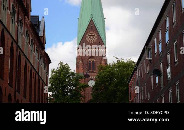 Brick church tower and clock standing between residential buildings in ...