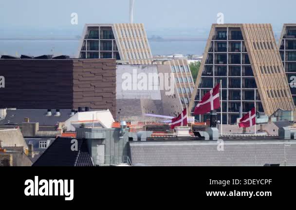 Danish flags waving over residential buildings with modern pyramid ...