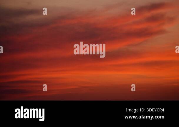 Sunset clouds creating a gradient of fiery red, orange, and golden hues ...