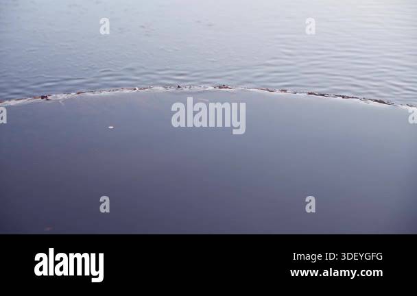 Smooth water surface gently rippling under soft ambient lighting with ...