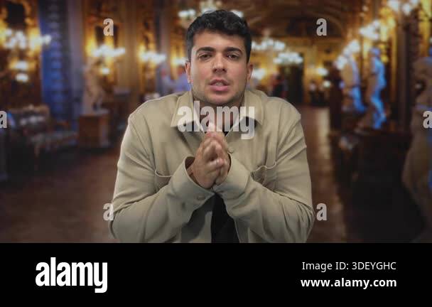 Man warms hands by rubbing them in hall as young hispanic guy at museum ...