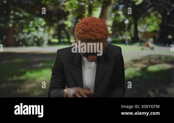 Young woman smiling and pointing finger at camera in bright sunlit lush ...