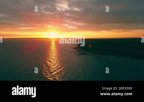 Golden hues envelop the horizon as the sun sets over calm waters ...