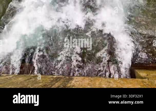 Top view of water flowing over a concrete dam structure, creating foam ...