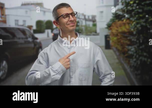Confident man in glasses pointing to himself on a sunny street showing ...