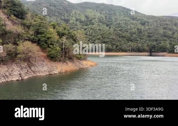 A calm body of water fills a mountain valley, bordered by a rocky ...