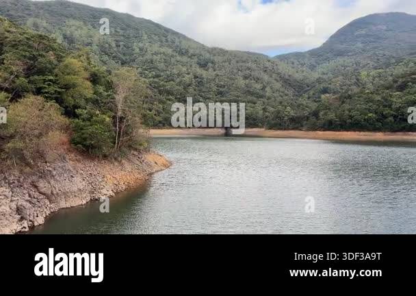 A calm body of water fills a mountain valley, bordered by a rocky ...