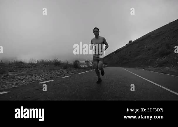 Caucasian man running on mountain asphalt road high in mountains ...