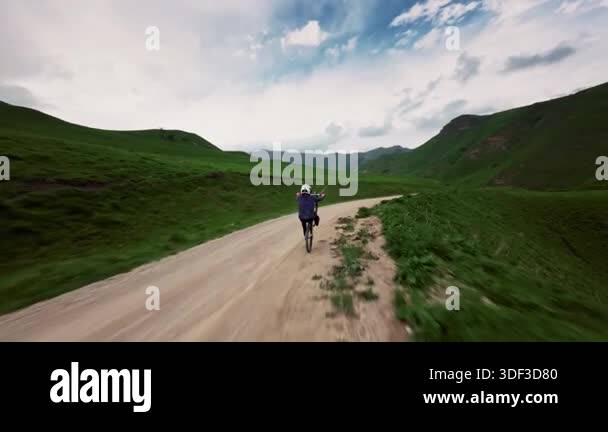 Aerial tracking fpv drone shot of biker cyclist doing manual rear ...