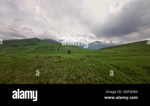 Side shot of cyclist riding mountain bike on green grass covered ...
