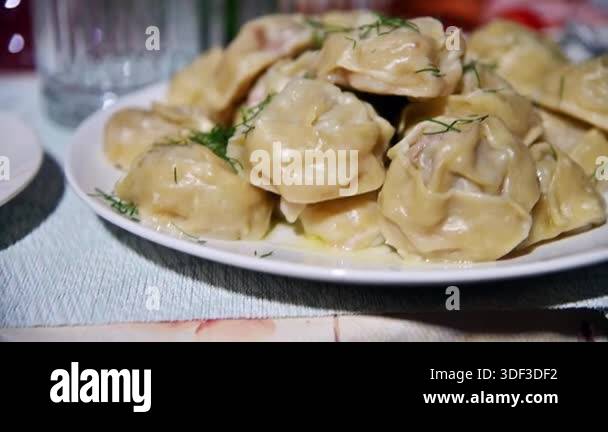 A close-up of freshly cooked manti lying on a plate. Traditional dishes ...