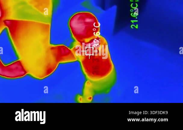 Adult holds a small baby, captured by a thermal imaging camera ...