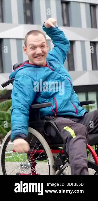 Positive young man with a disability sitting in a wheelchair, joyfully ...
