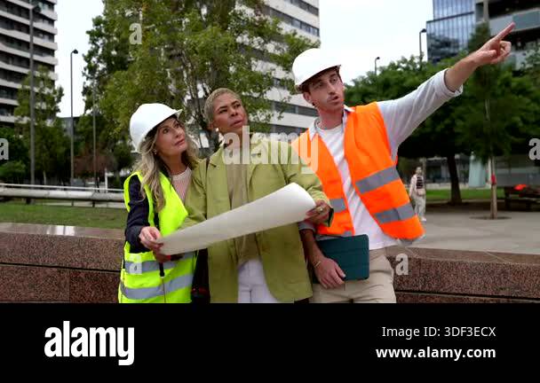 Diverse team of architects and civil engineers reviewing blueprints and ...