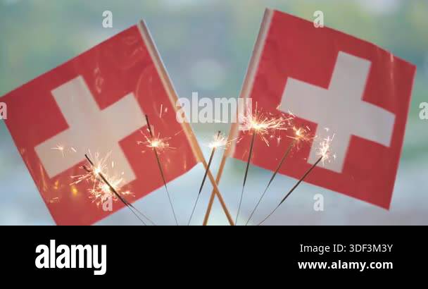 Two Swiss flags are held upright while sparklers light up the ...