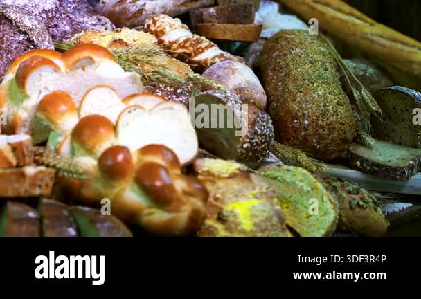 Bakers show a variety of breads at their market stand. Customers browse ...