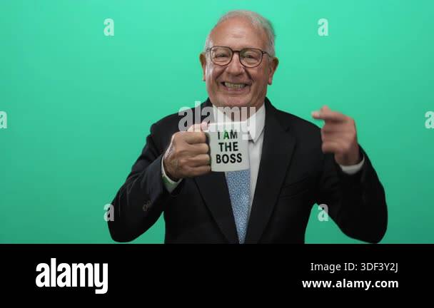 Senior man in a business suit smiles while holding a mug with 'i am the ...