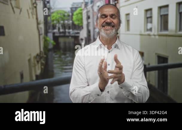 Man clapping hands on an amsterdam canal street by a waterway and ...