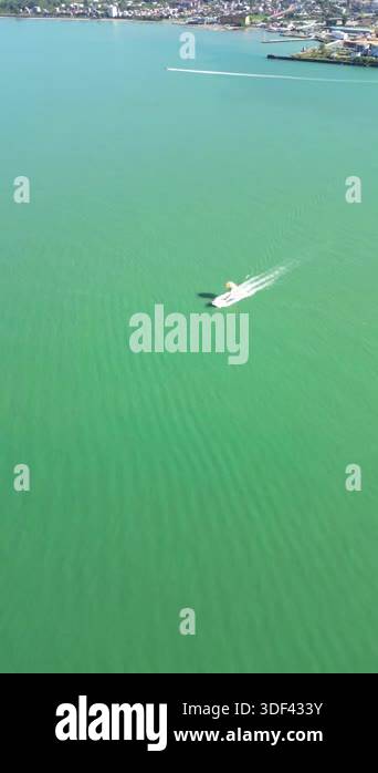 Vertical drone parasailing over green water. 4K vertical footage shows ...