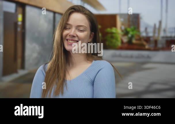 Woman with brown hair smiles showing face in front of building entrance ...